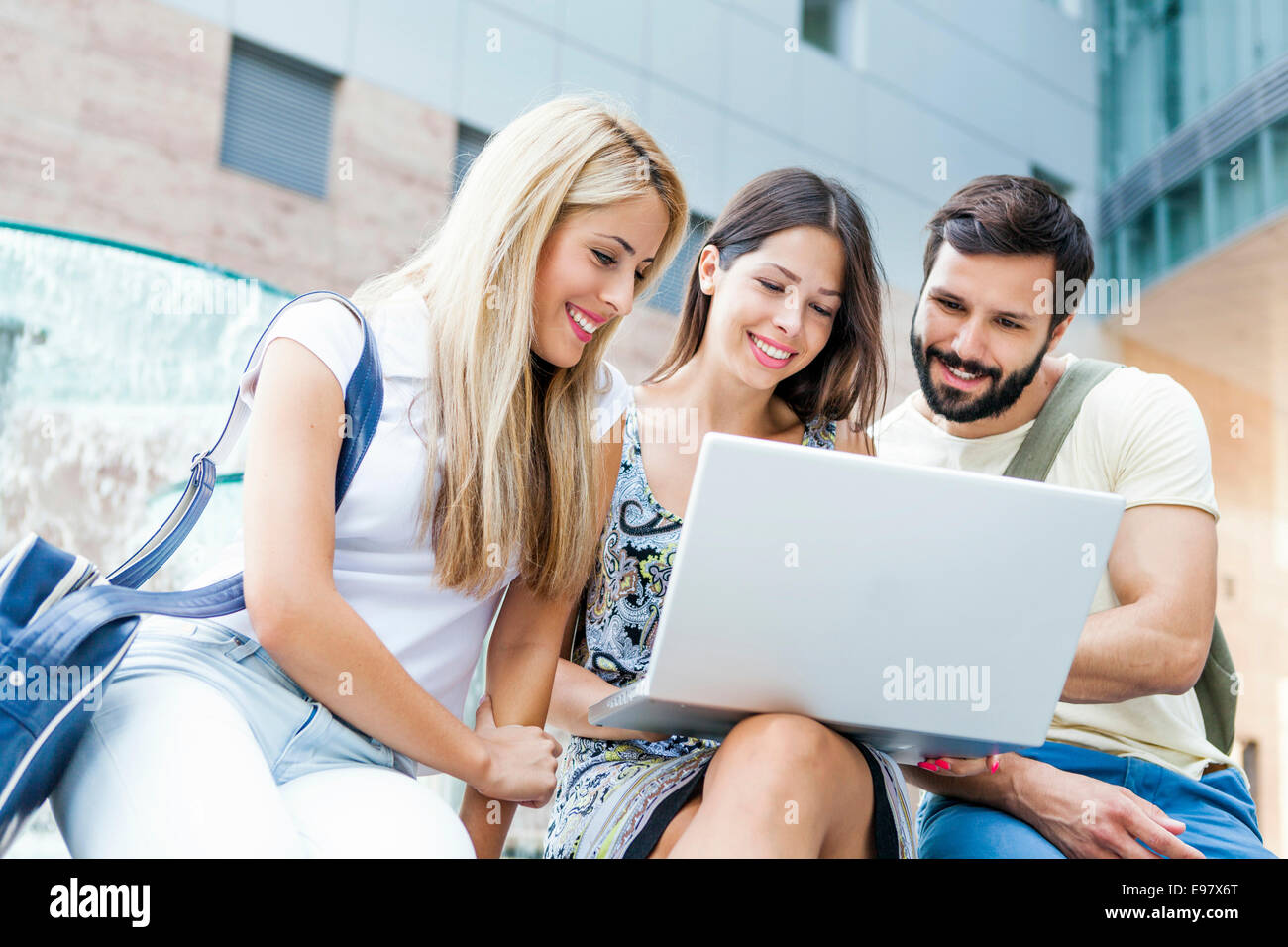 Three students using laptop together Stock Photo - Alamy