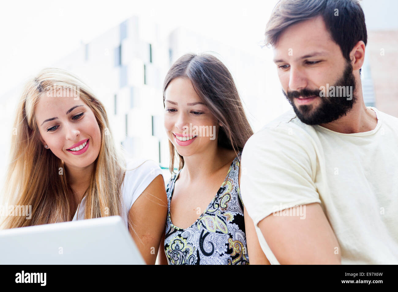 Three students using laptop together Stock Photo - Alamy
