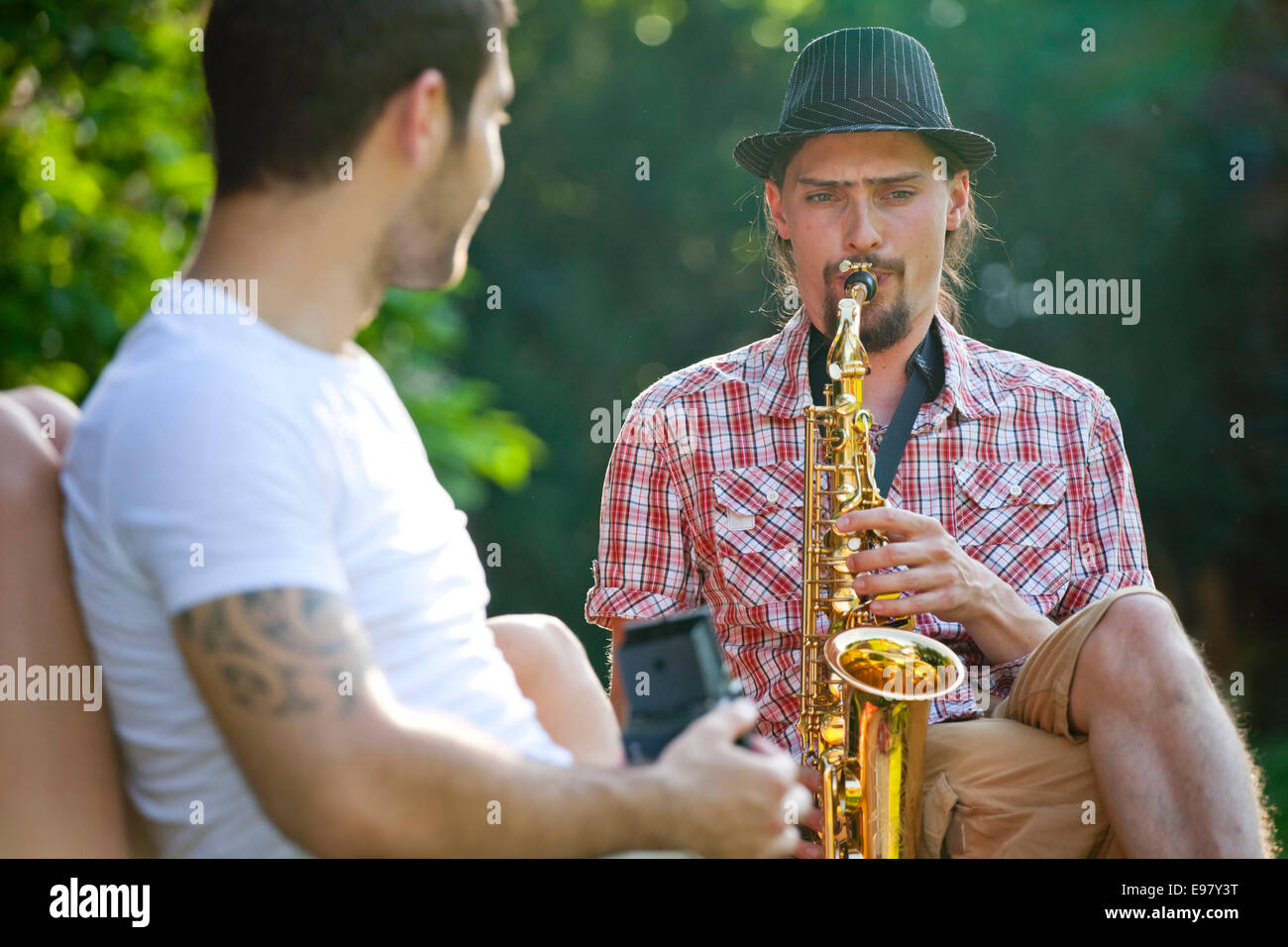Young man playing saxophone, friend is listening Stock Photo - Alamy
