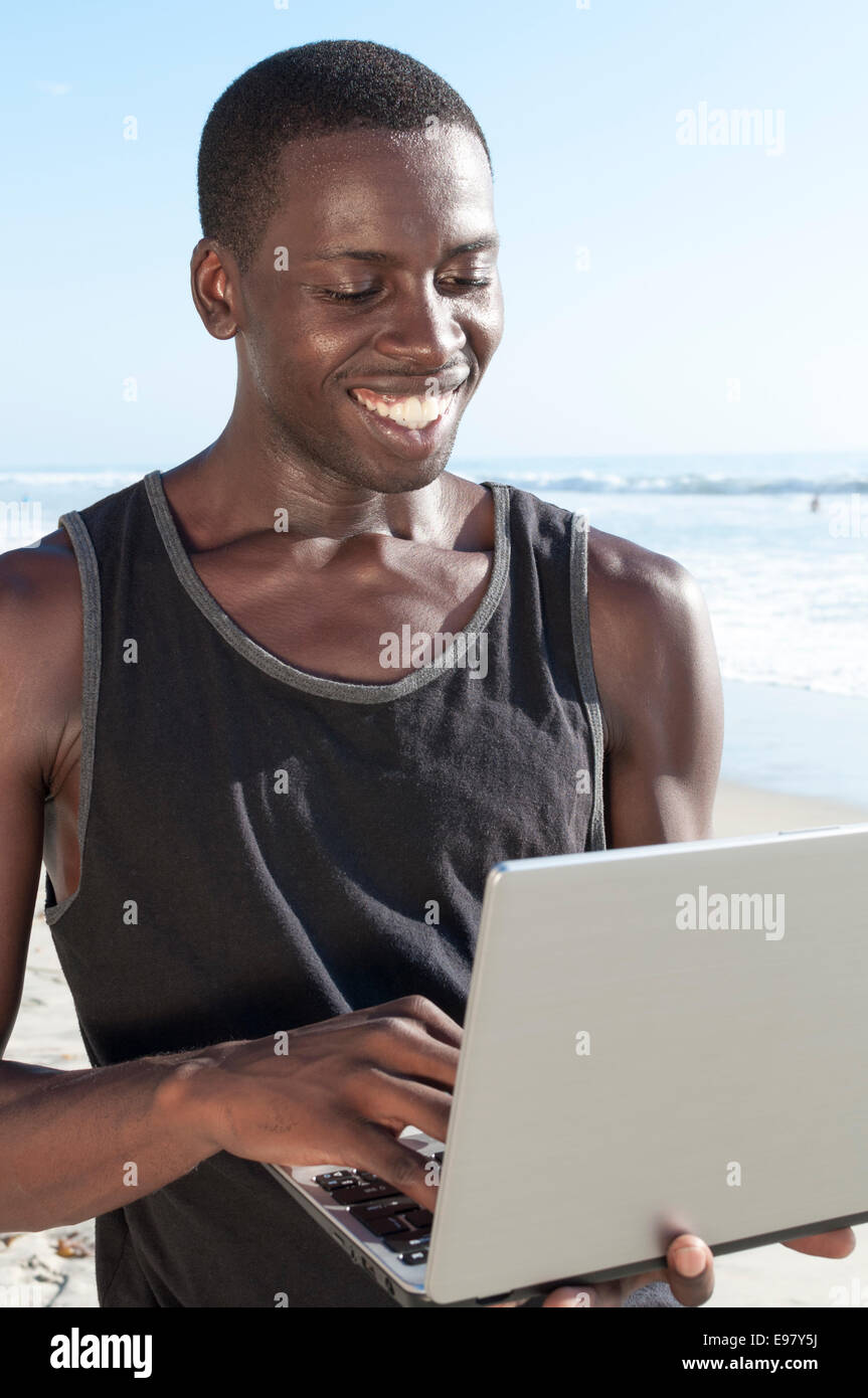 Young lean handsome African American man smiles while surfing the net ...