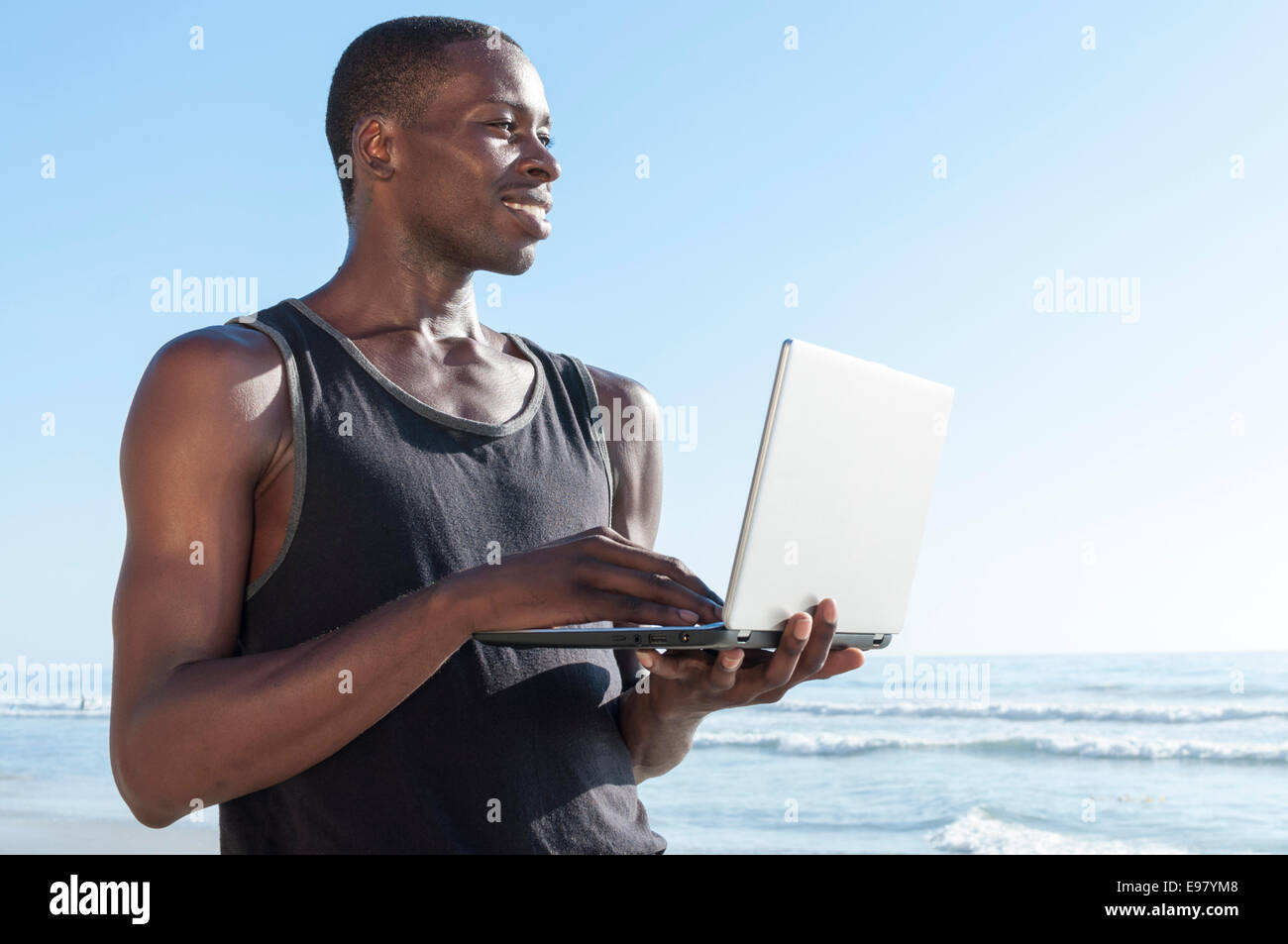 Handsome lean young African American man smiles as he observes activity ...