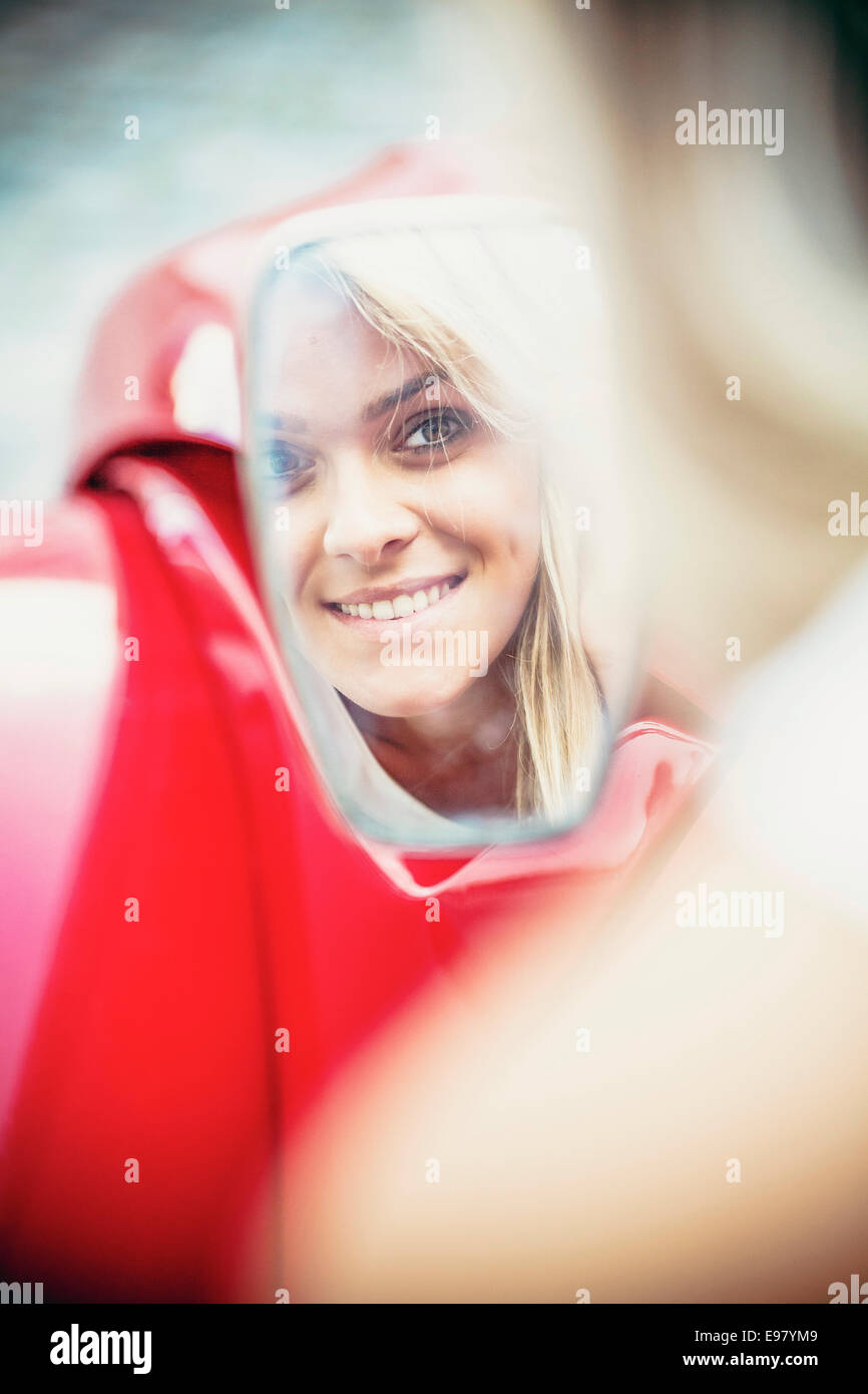 Young woman looking into rear-view mirror of car Stock Photo - Alamy