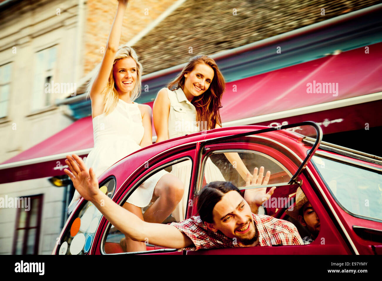Young people driving in vintage car waving happily Stock Photo - Alamy