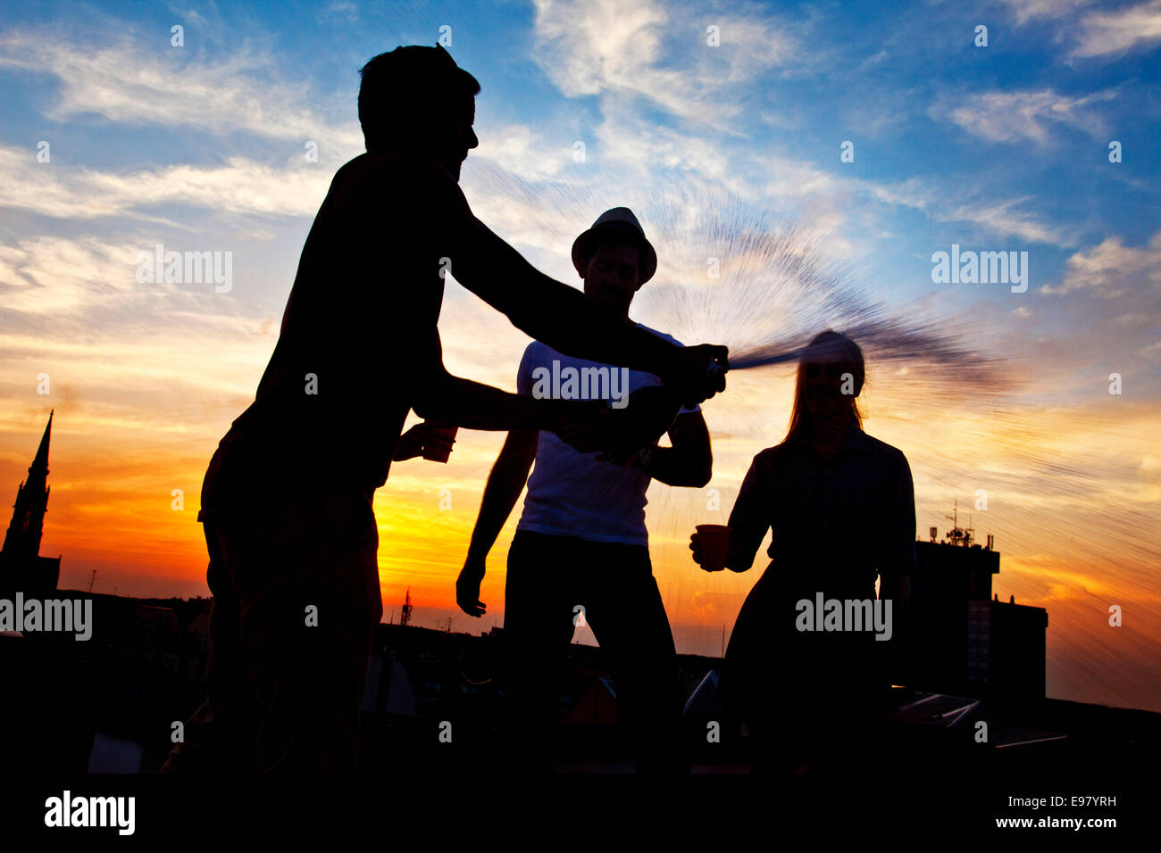 Young people fooling around with champagne bottle at sunset Stock Photo ...