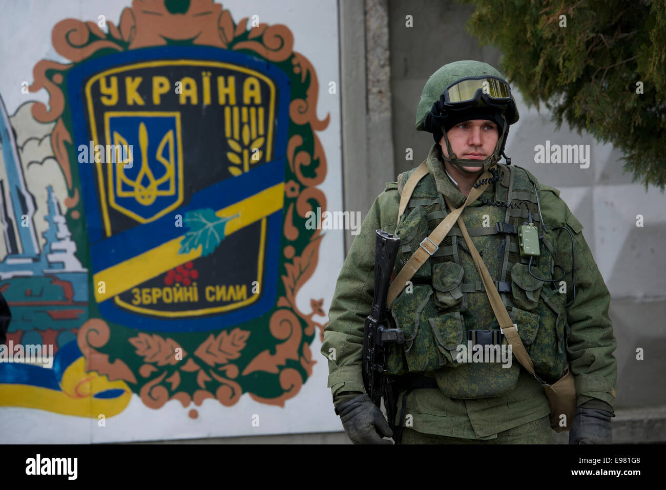 Armed Russian soldier stands guard in front of a Ukraine insignia ...