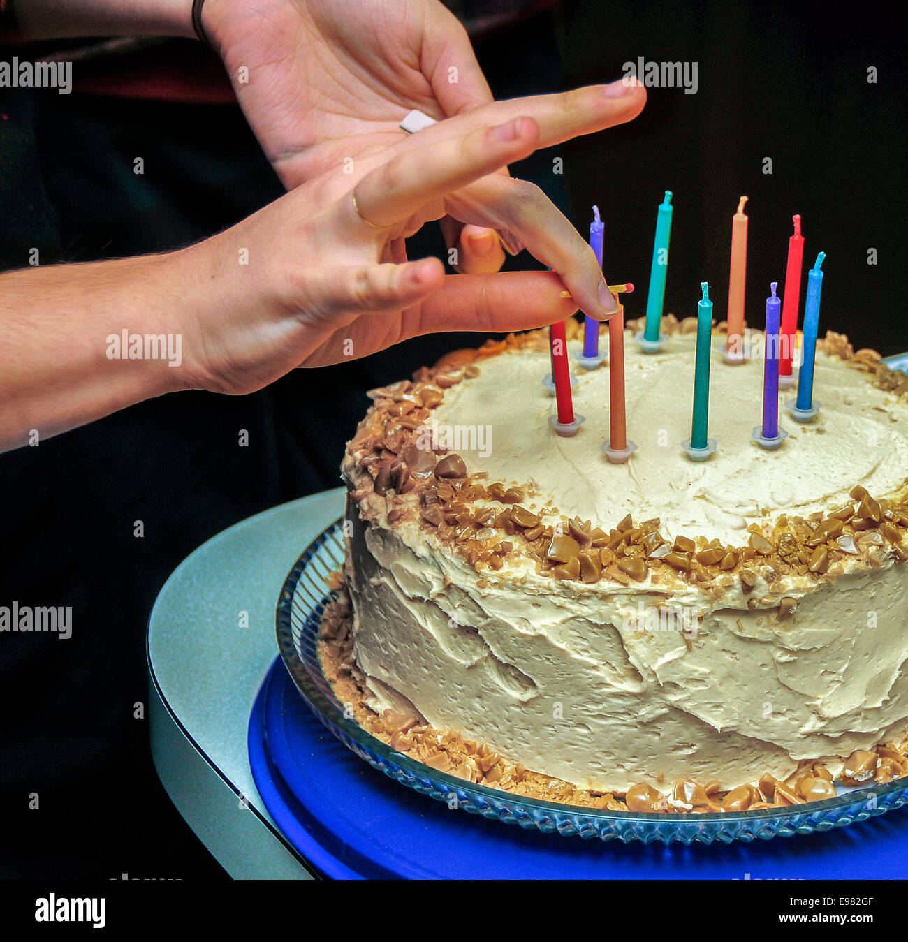 Against black background two hands lighting 9 multicolored birthday ...
