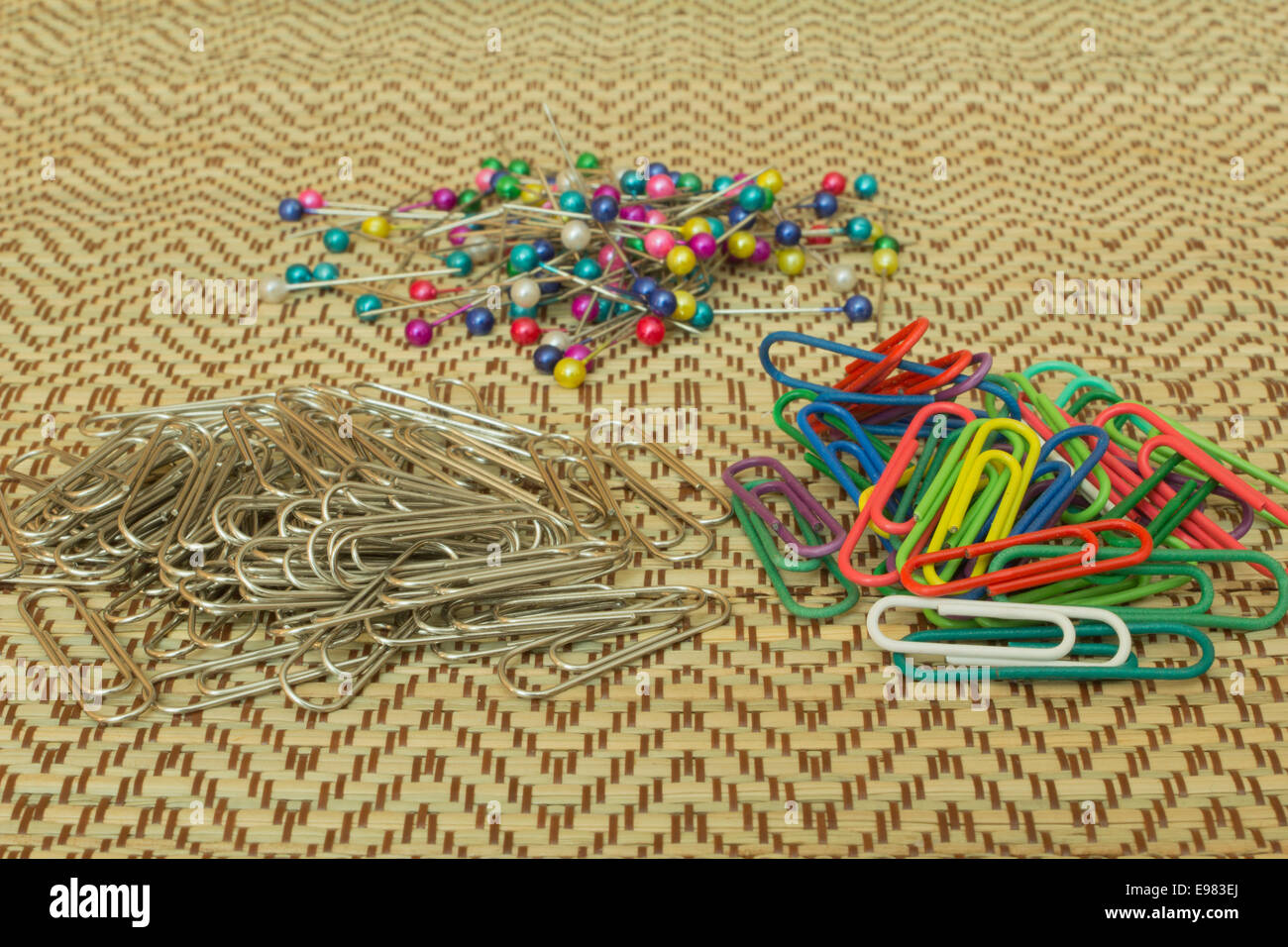 Stationery pins and paper clips on a straw background Stock Photo - Alamy