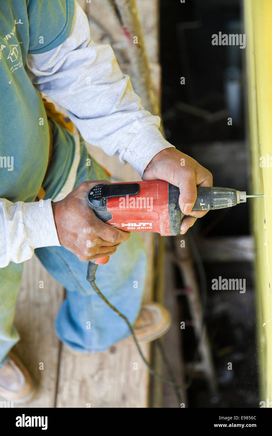 Worker installing wall system materials and insulation over frame of ...