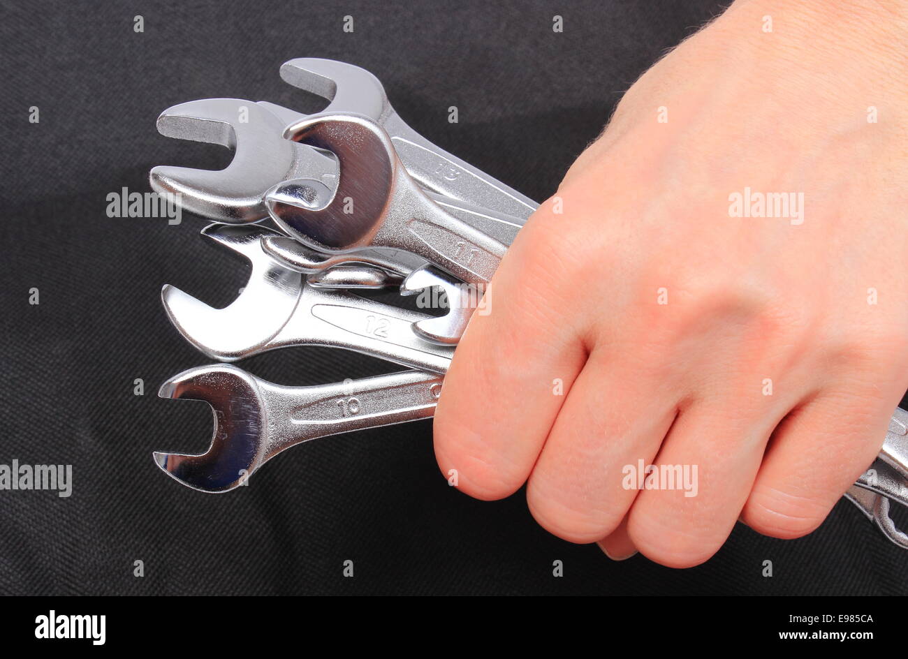 Hand of woman holding wrenches on black background Stock Photo - Alamy