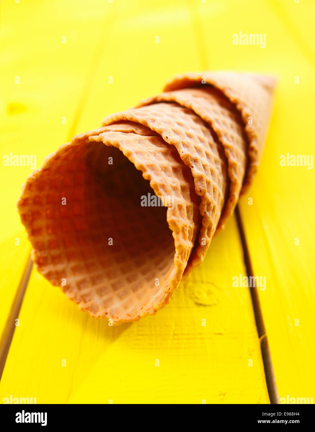 Close up shot of four Ice cream cones on yellow table Stock Photo - Alamy