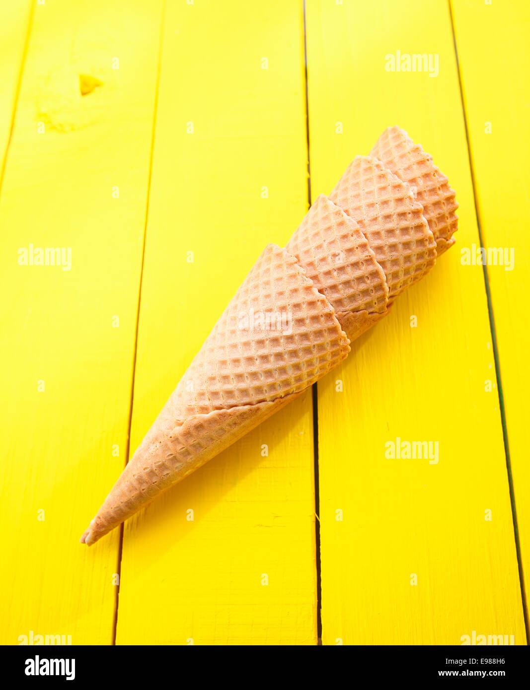 Four ice cream cones on yellow table Stock Photo - Alamy
