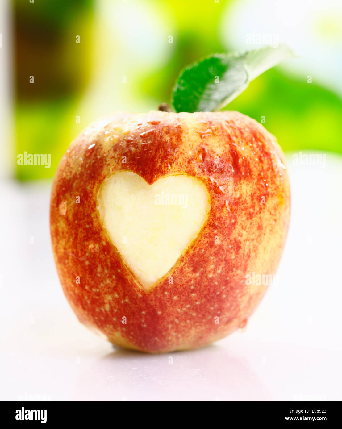 A juicy fresh ripe red apple with an incised heart shape in the skin ...