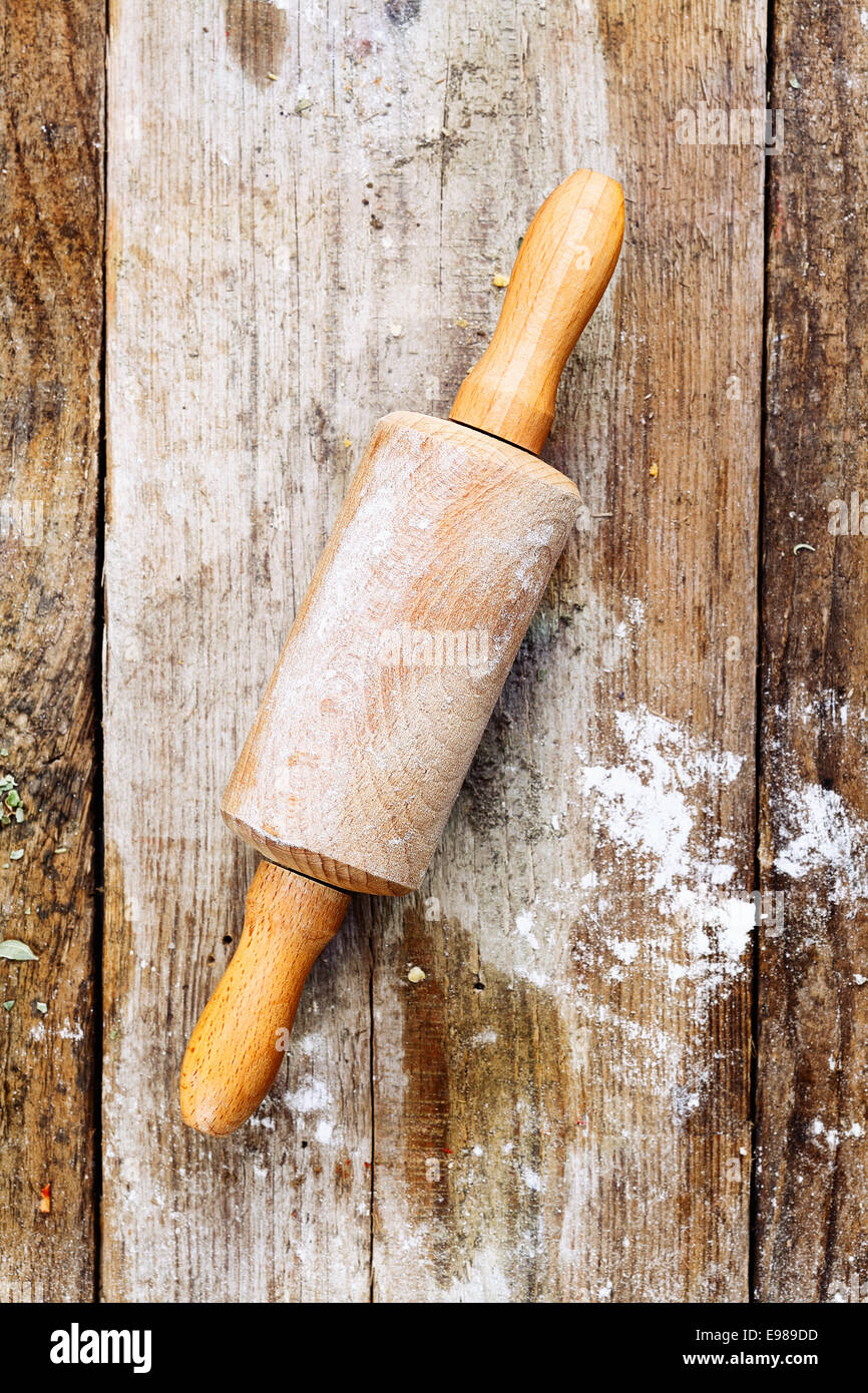 Wooden rolling pin with remnants of flour in a rustic kitchen on an old ...