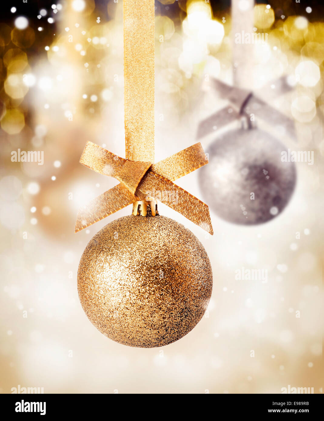 Hanging golden textured Christmas bauble with falling snow against a ...
