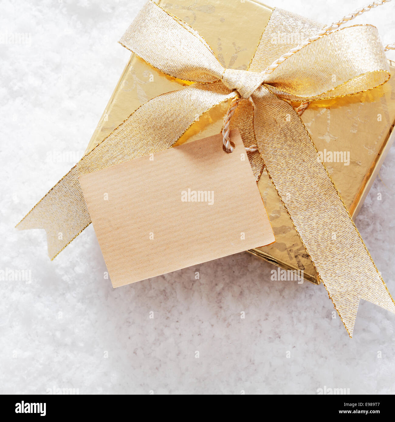 Gold Christmas giftbox with blank paper label and decorative ribbon and ...