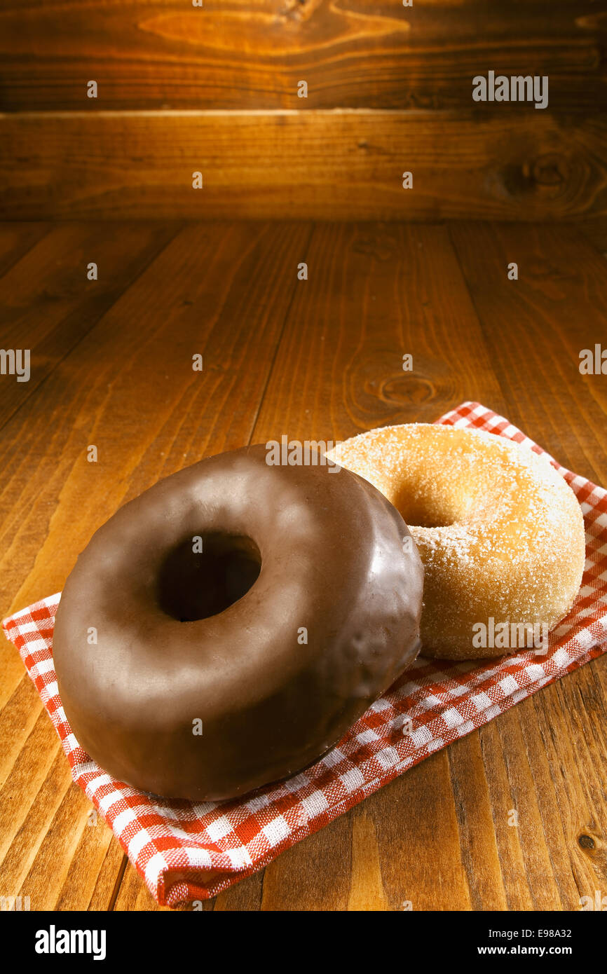 Delicious fresh chocolate doughnut resting on a golden sugared one on a ...