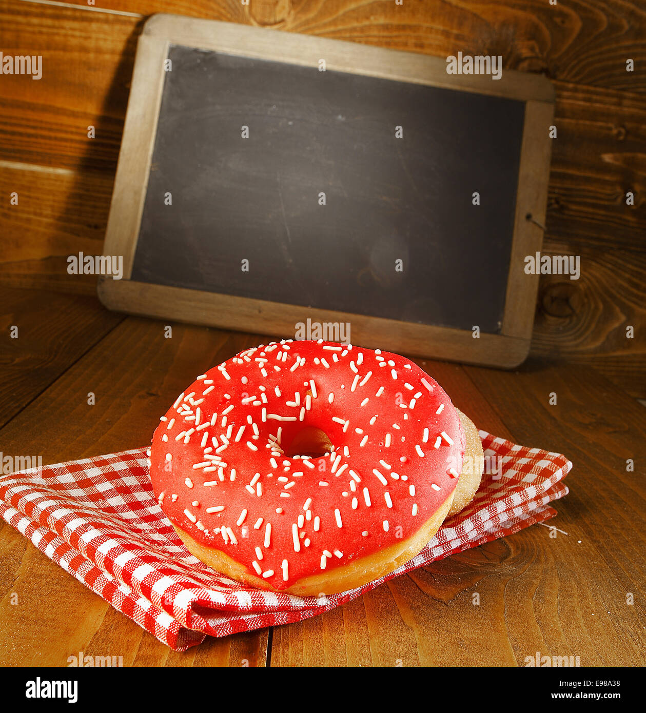 Red glazed fresh doughnut topped with sprinkles served on a red and ...