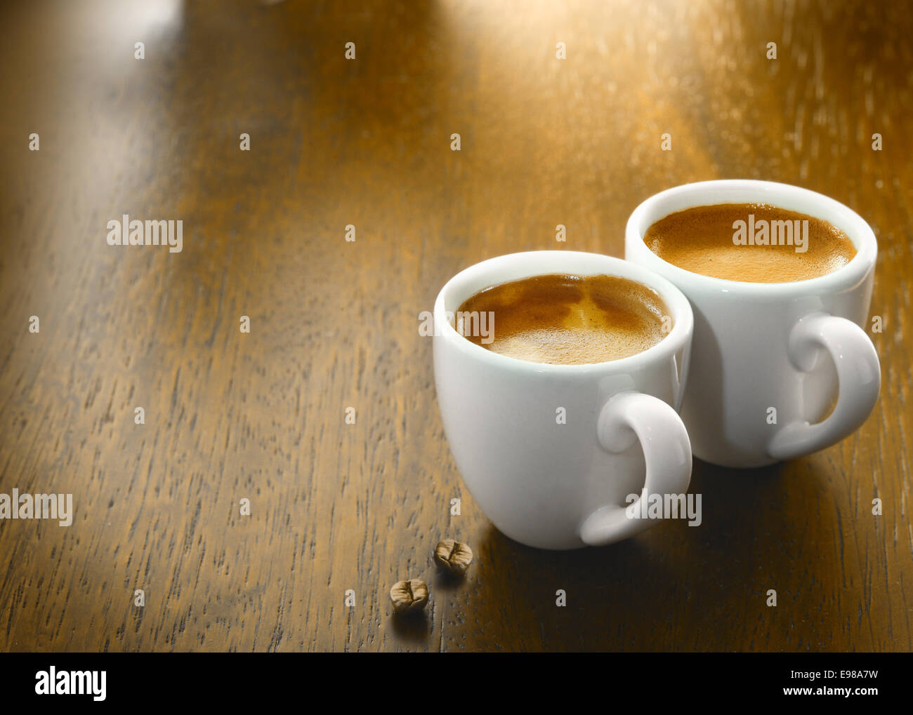 Two cups of freshly brewed espresso coffee with two single coffee beans ...