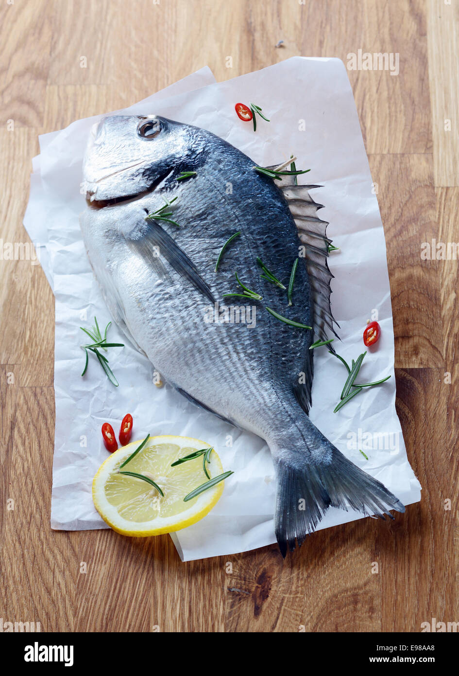 Whole fresh fish lying with the tail towards the camera on a sheet of ...