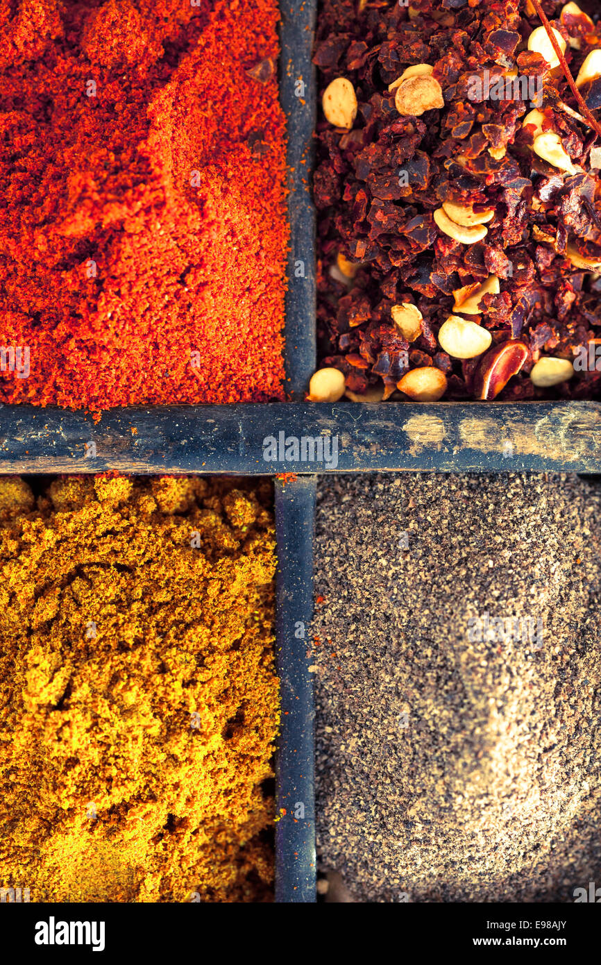 Overhead view of four colourful spices with black pepper, chilli, red ...