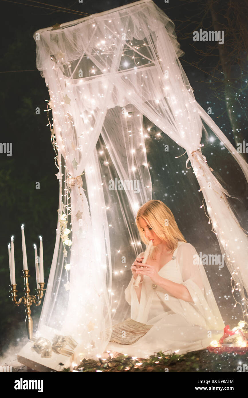 Beautiful Christmas angel in a forest sitting under a white lace canopy ...