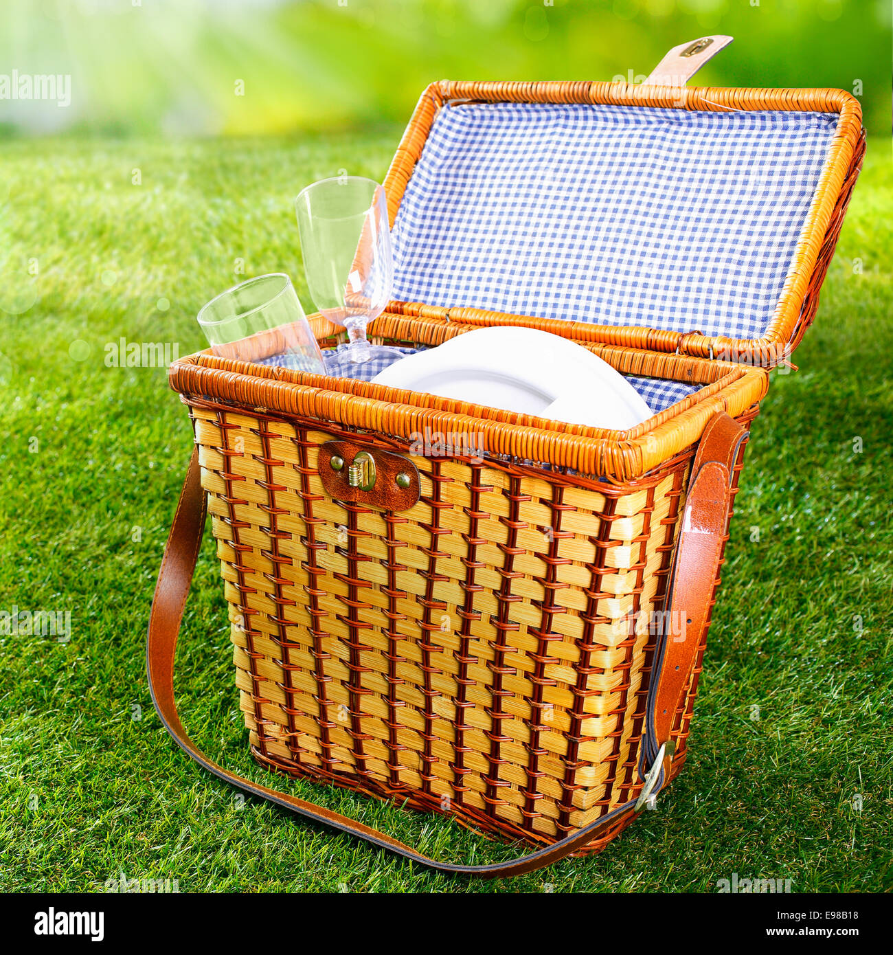 Fitted wicker picnic basket or hamper standing on fresh lush green ...