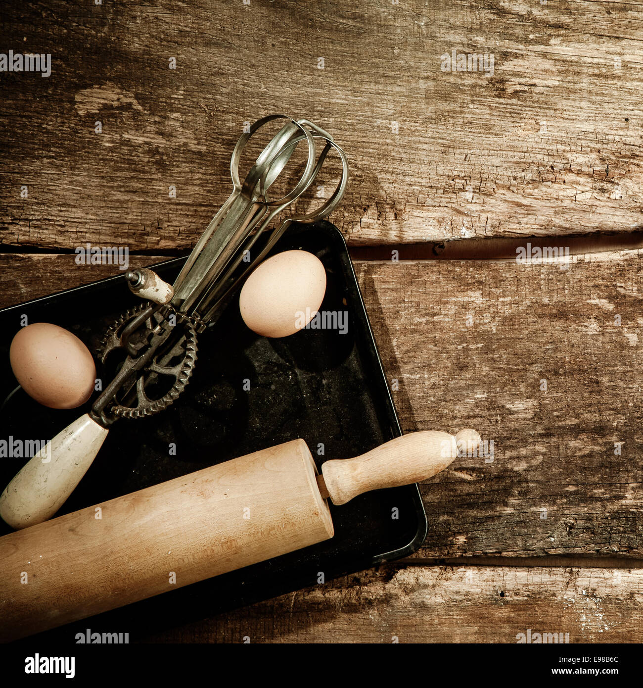 Baking concept with a wooden rolling pin and old egg beater resting on ...