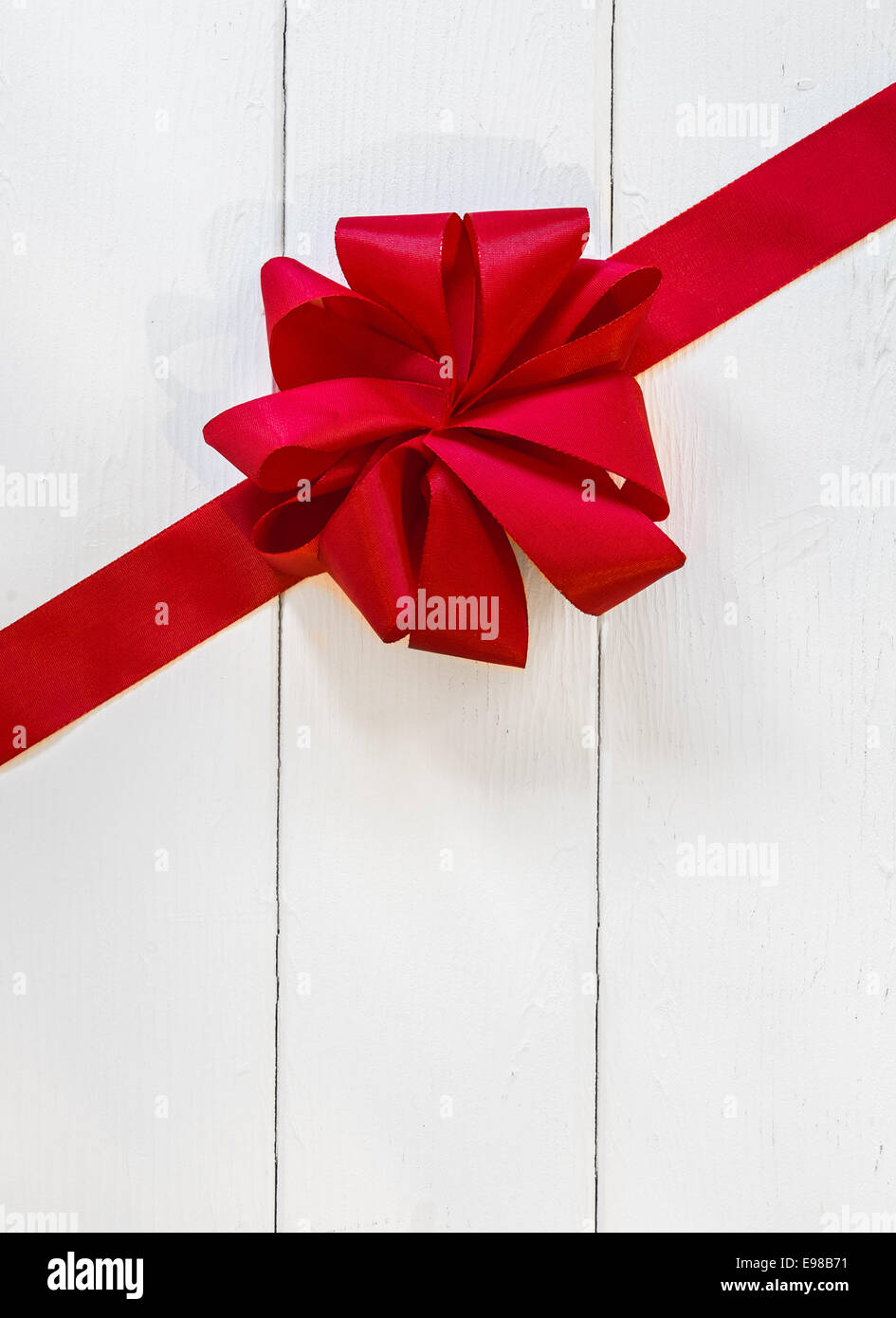 Decorative red bow and ribbon on rustic white painted wooden boards ...