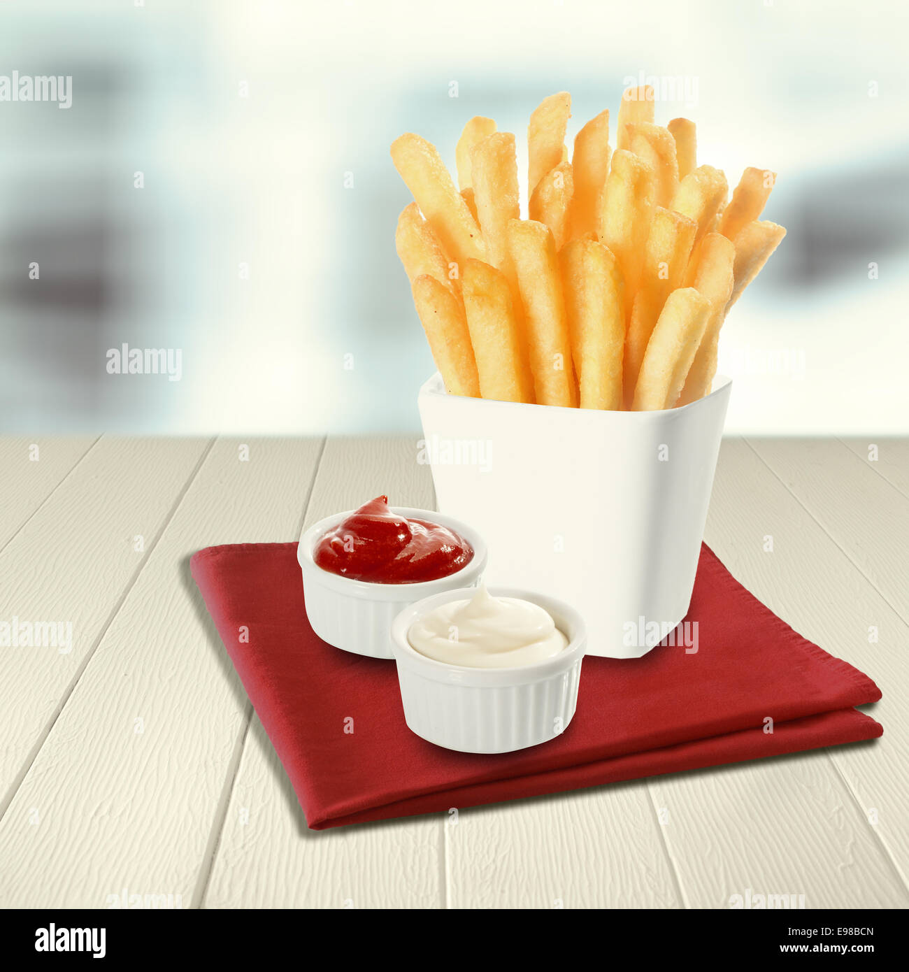 Crisp fried potato batons or chips standing upright in a white ceramic ...