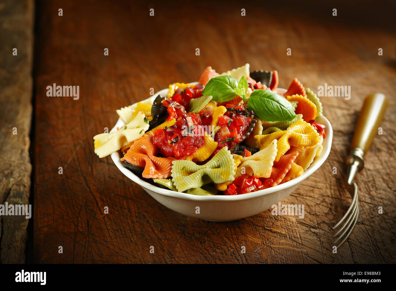 Multicoloured Italian bow tie pasta topped with tomato and garnished ...