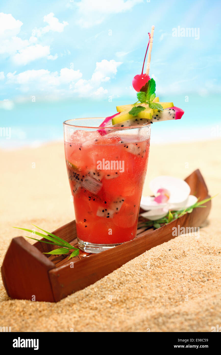 A glass of fresh cold tropical fruit cocktail on a sunny beach, close ...