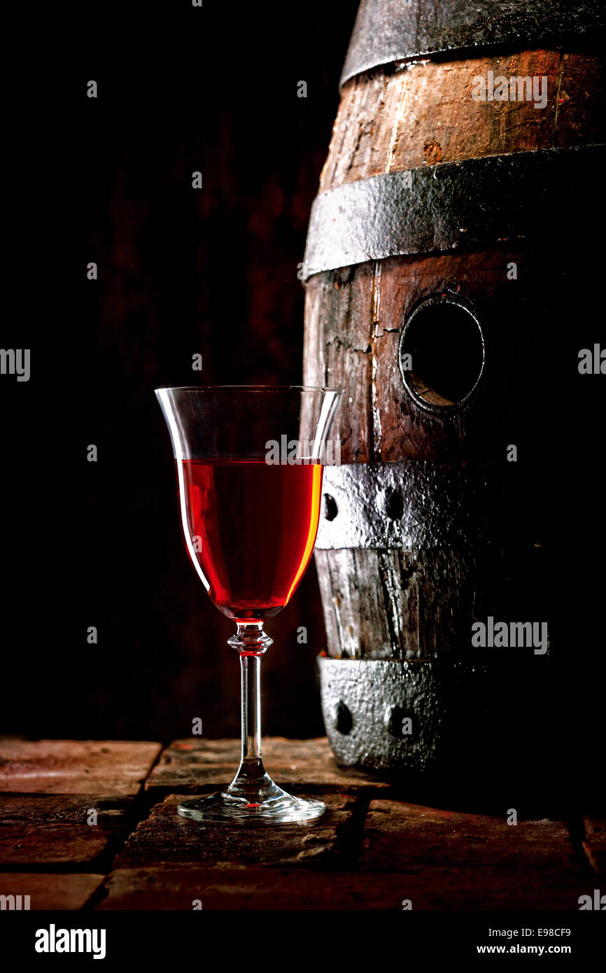A glass of red wine next to an old oak cask with its stopper out Stock ...