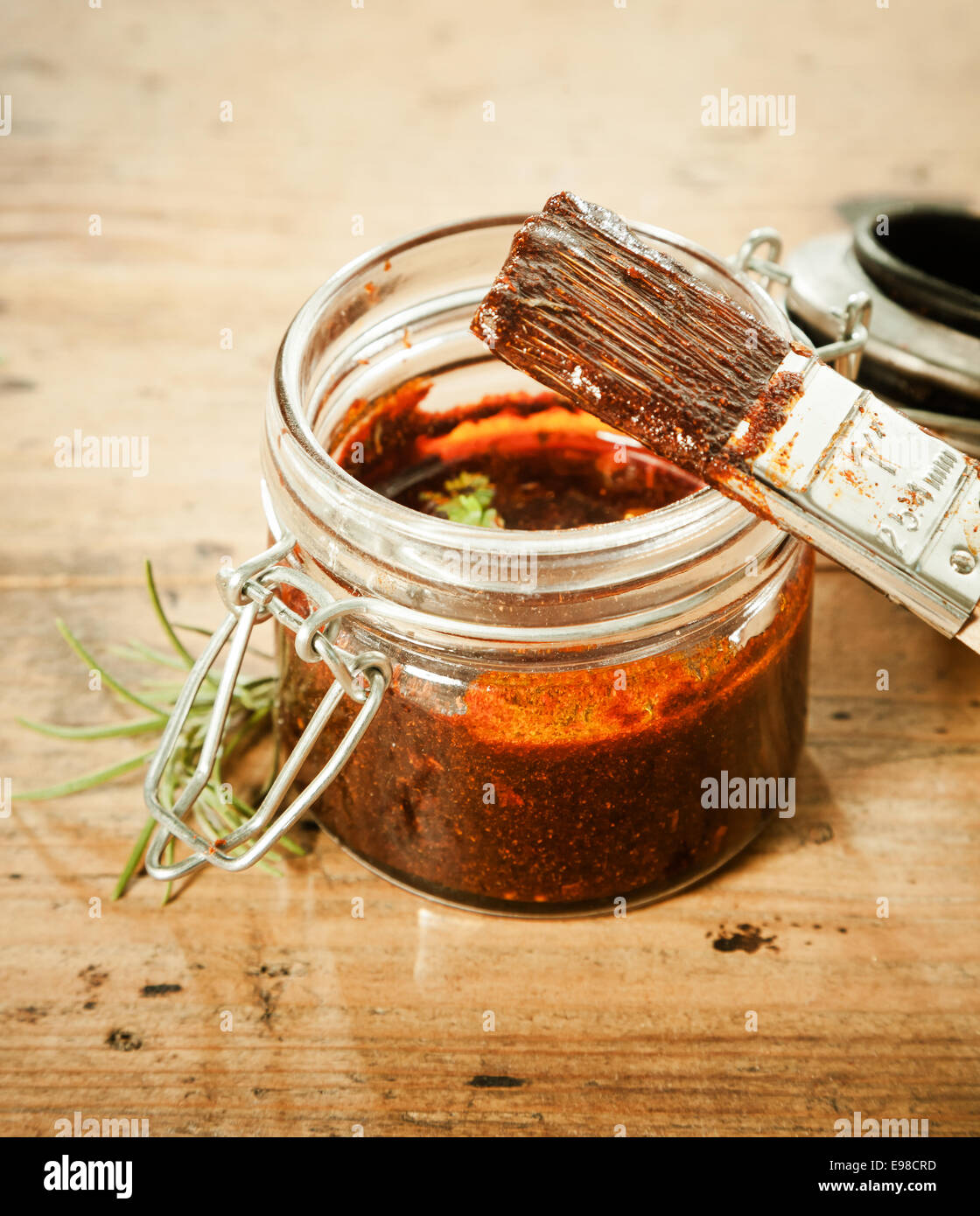 Savoury BBQ basting sauce in a glass jar with a basting brush and sprig ...