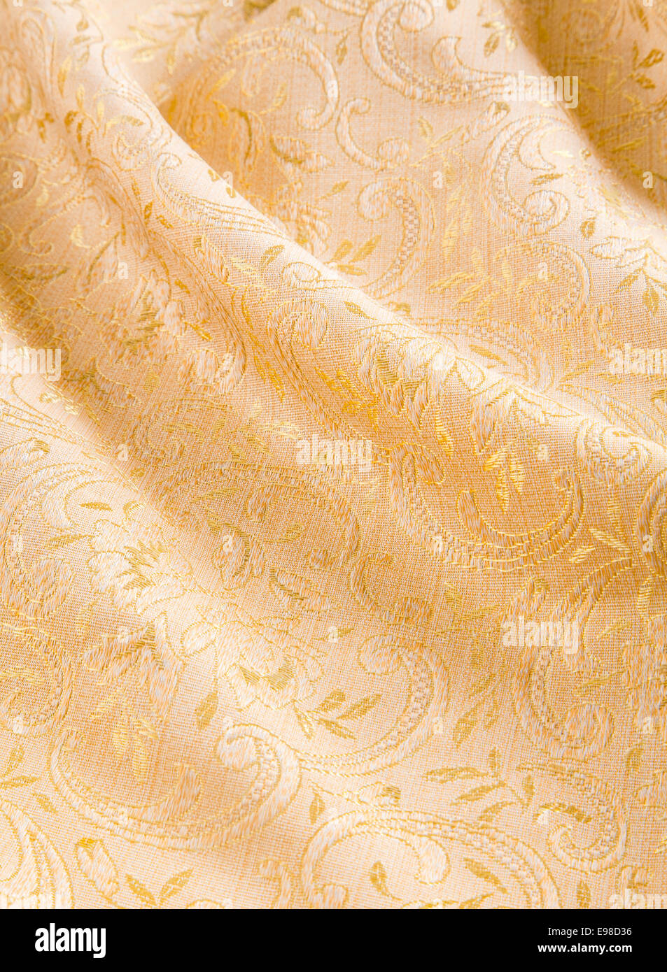 Soft folds of draped gold damask with a shiny floral pattern for a ...