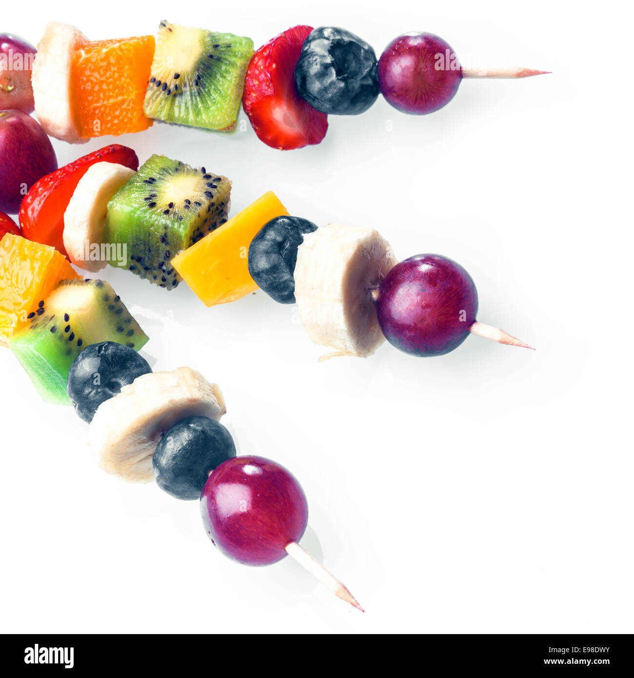 Trio of colourful tropical fruit kebabs arranged in a fan with grapes ...