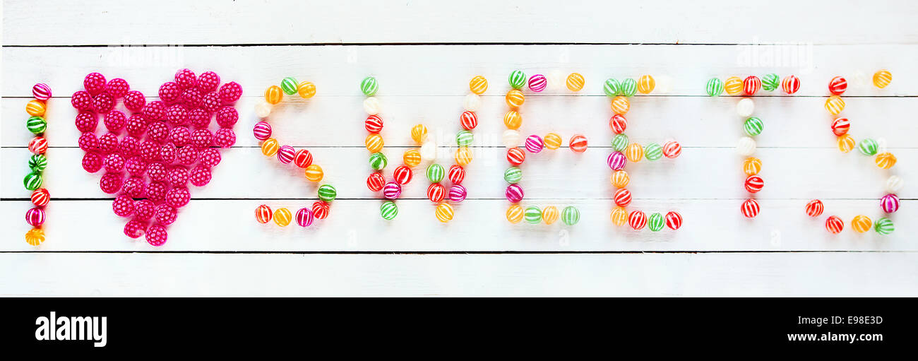 I love sweets written with several types of candies over a white wooden ...
