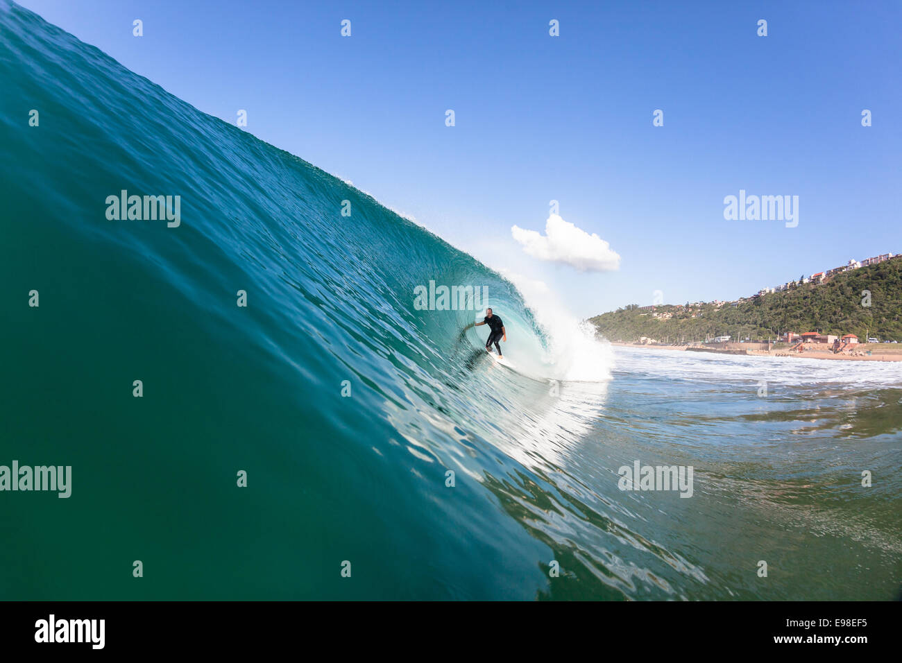 Surfing Surfer Rides inside hollow blue wave closeup swimming water ...