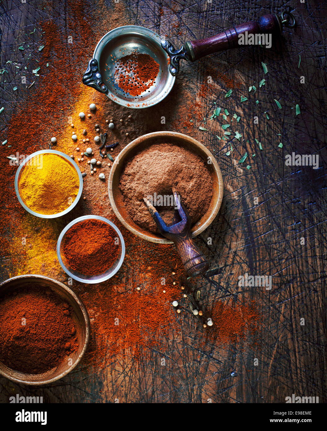 Overhead view of colourful dried ground spices in bowls spilling onto ...