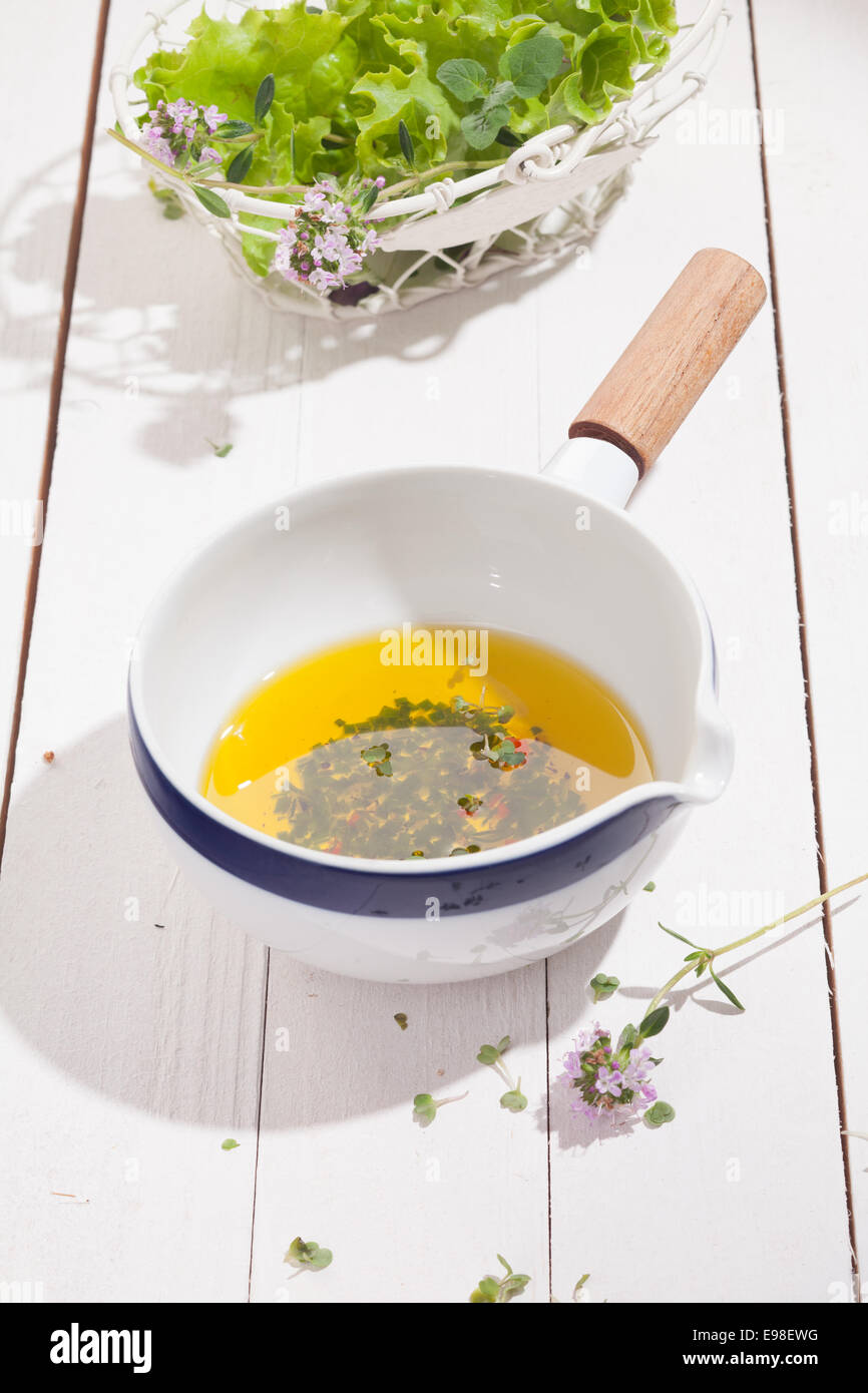 Ceramic dish of golden olive oil and chopped fresh herb salad dressing ...