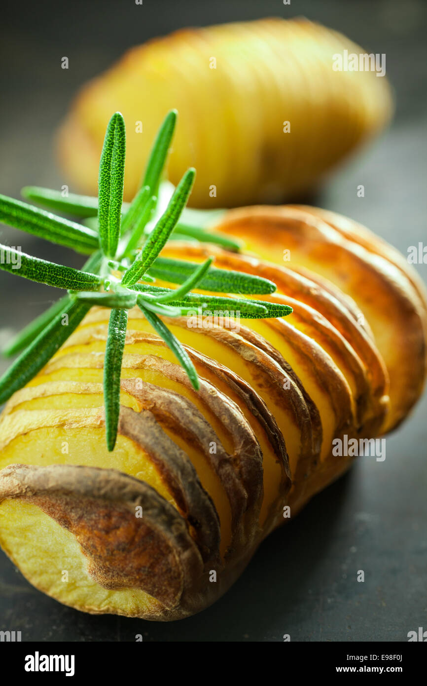 Baked potato cooked in foil on a barbecue and sliced through served ...