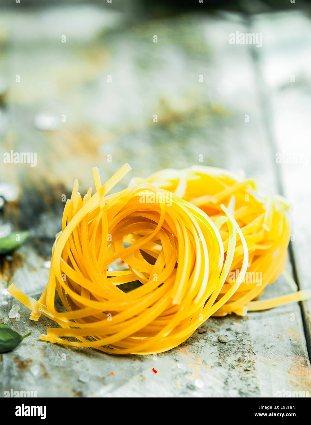 Uncooked linguini Italian pasta lying on an old grunge rustic wooden ...