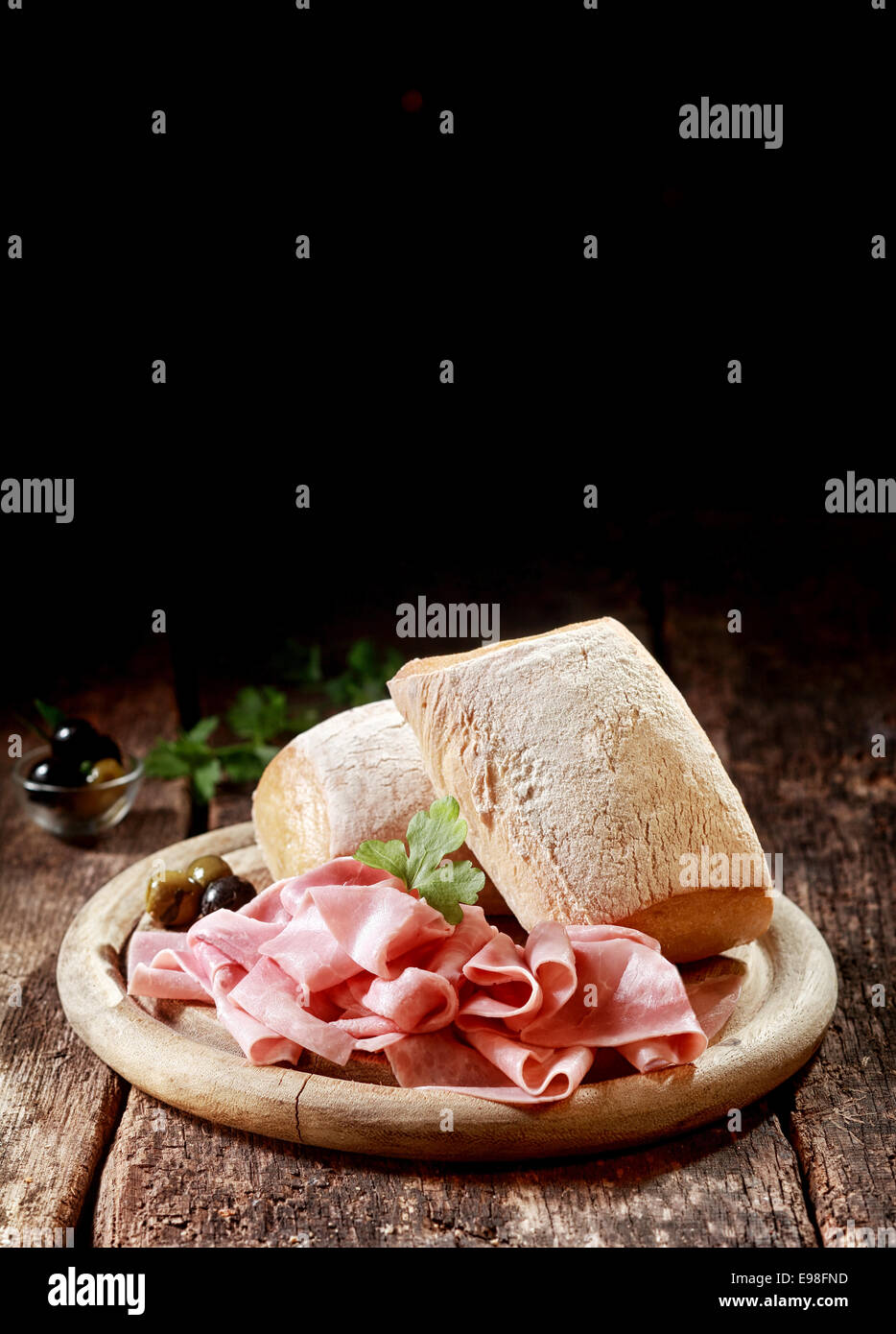 Cured thinly sliced German ham with crusty rolls for a country lunch ...