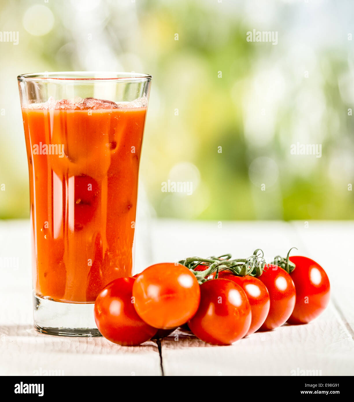 Glass of freshly prepared tomato juice with a bunch of fresh ripe red ...