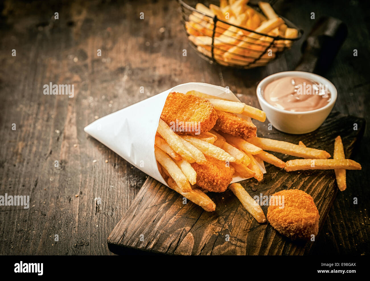 Serving in a paper cone of takeaway crumbed fried fish nuggets with ...