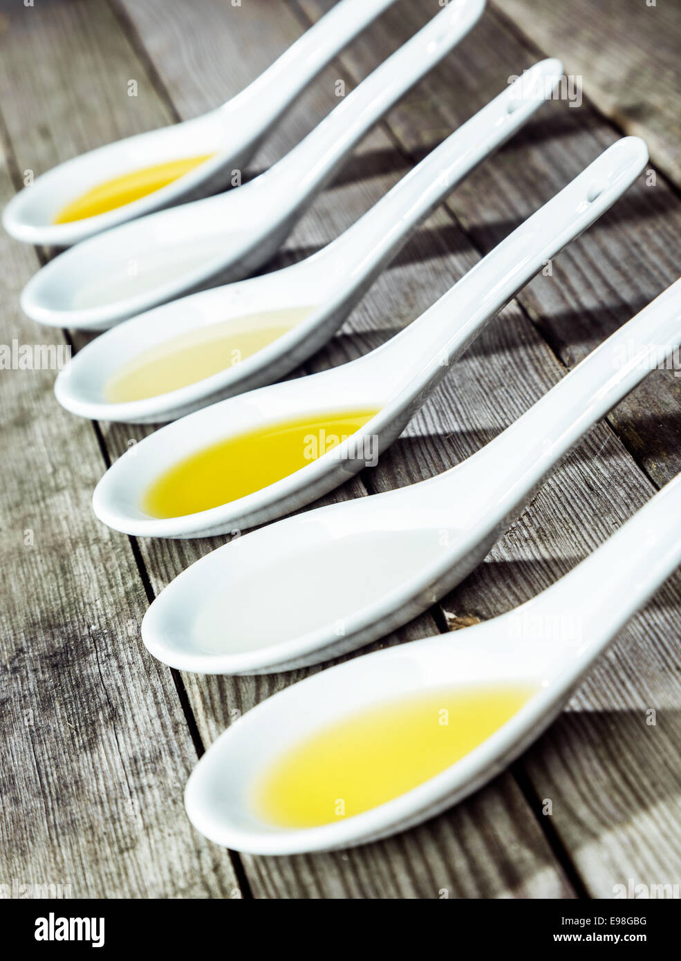 Row of ceramic spoons with various oils and salad dressings used in ...