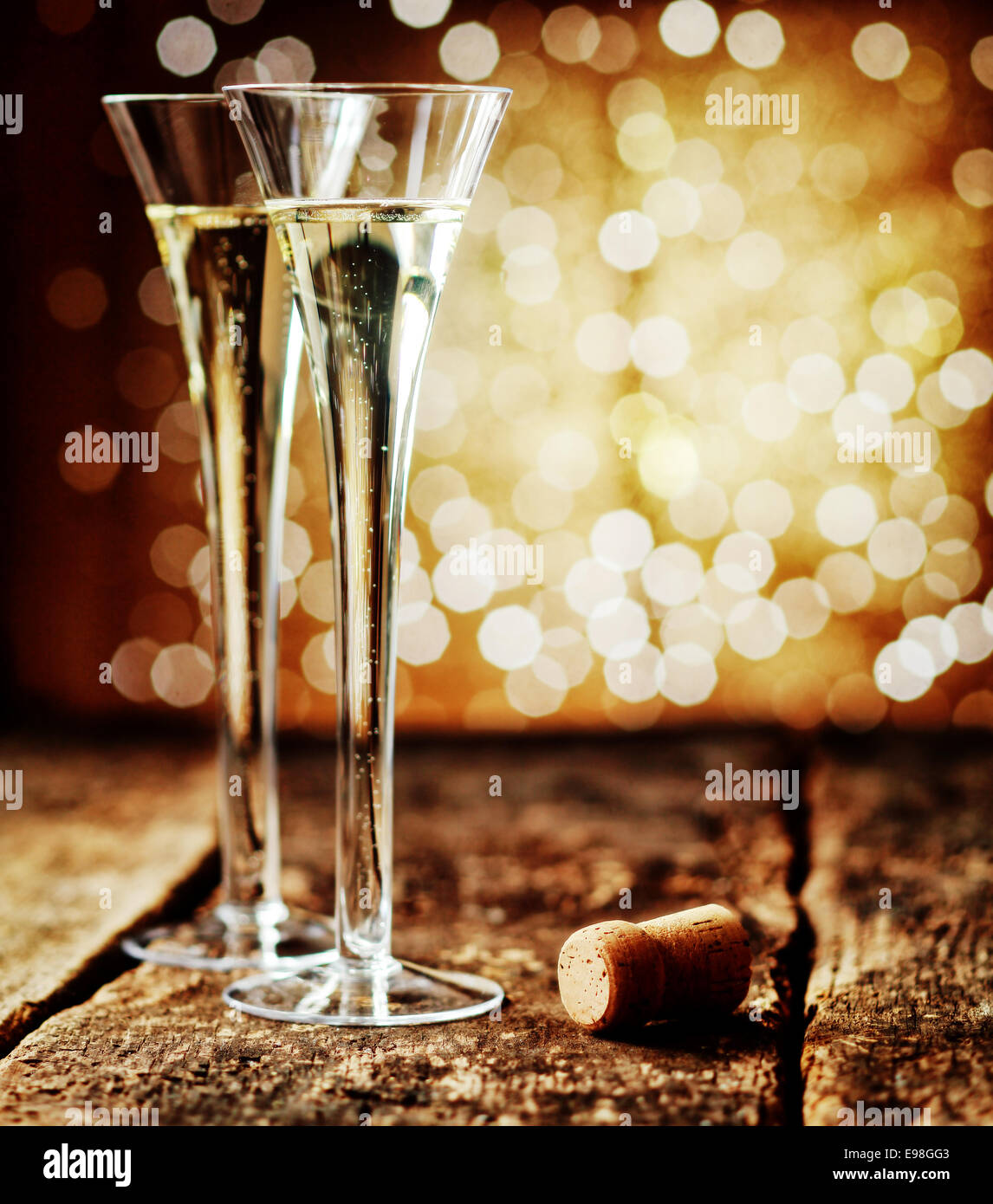 Two tall elegant flutes of romantic champagne on an old rustic wooden ...