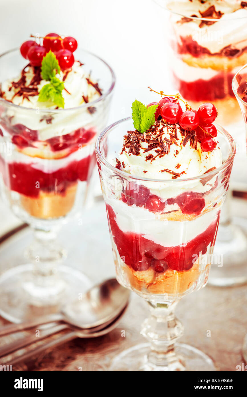 Tall glasses of colorful layered redcurrant and ice cream parfait ...