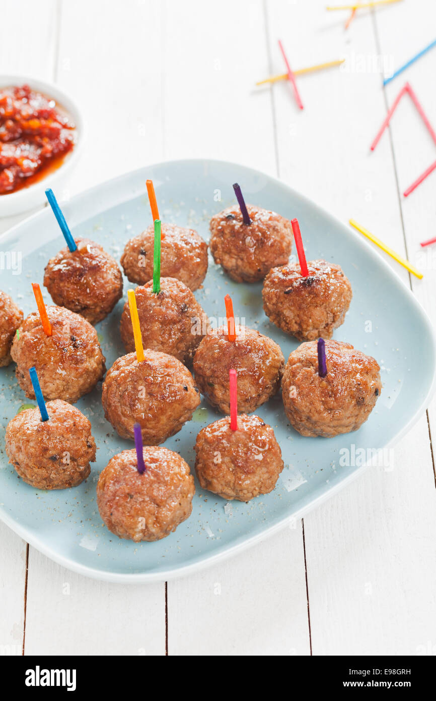 Preparing a tray of delicious spicy seasoned meatballs with colored ...