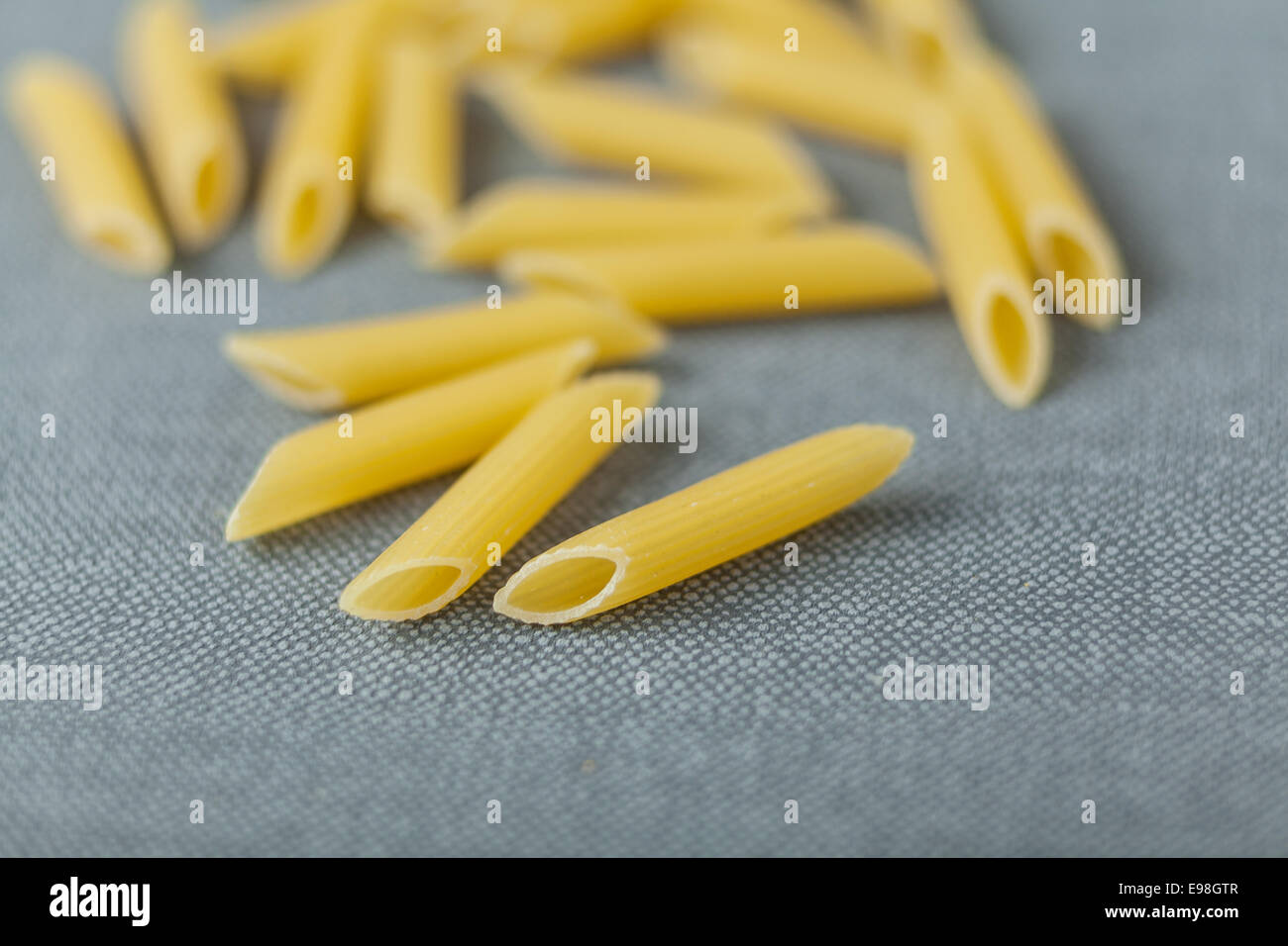 Scattered dried penne rigate Italian pasta with its ridged tubes to ...