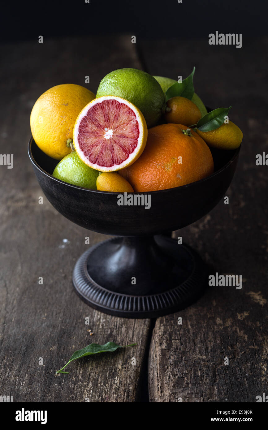 Pedestal bowl of assorted fresh citrus fruit with a halved blood orange ...